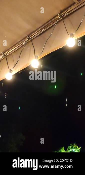 Raindrops dripping from yellow roof with shining lanterns against black ...