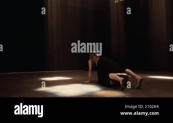 A female dancer lies on the floor in a dramatic final pose, concluding ...