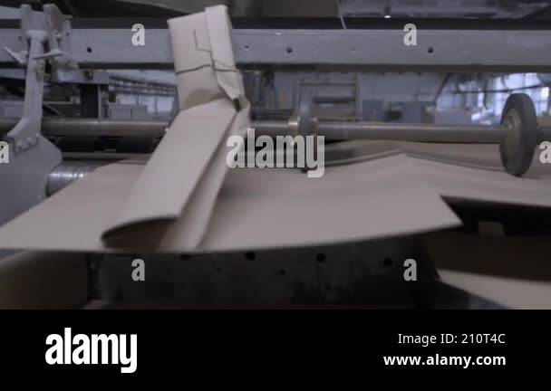Large machine rollers move cut cardboard sheets in shop. Special ...
