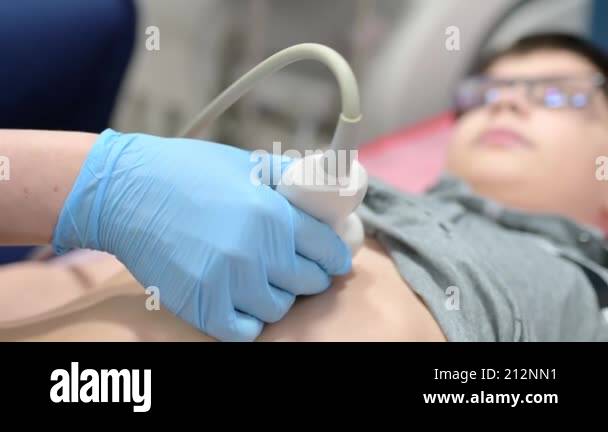 Doctor making abdominal ultrasound for boy using scanner machine ...