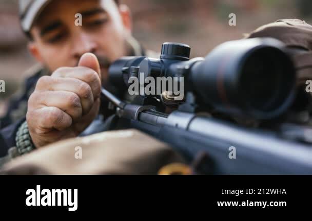 Hunter carefully unloads a bullet into his rifle, preparing for a hunt ...