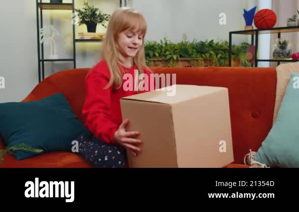 Happy young child girl unpacking delivery parcel. Smiling satisfied ...