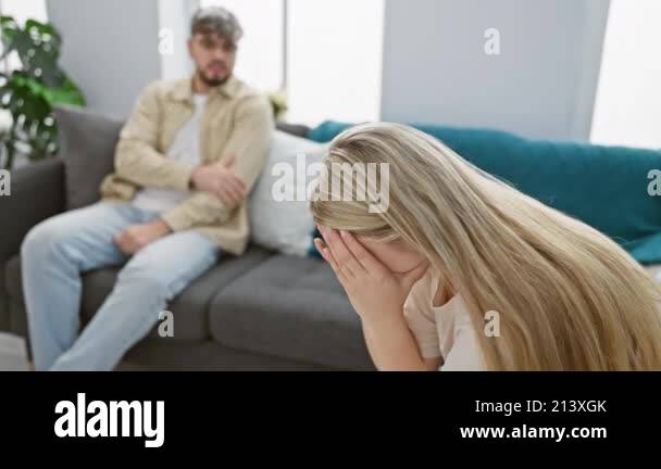A woman crying in a living room with a concerned man sitting behind ...
