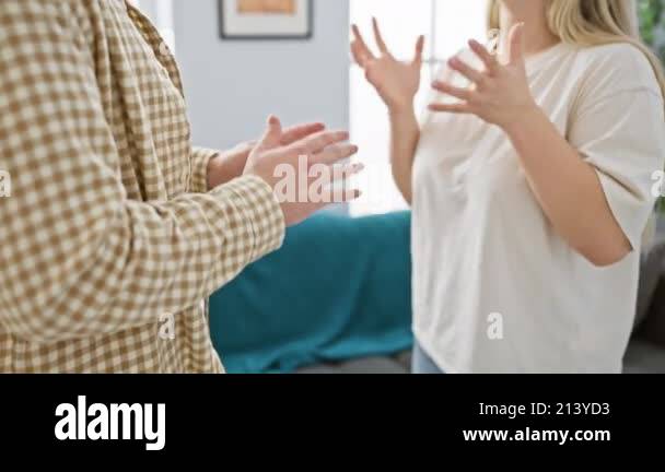 Two people communicating with hand gestures in a cozy living room ...