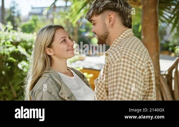 A loving couple shares a tender kiss outdoors in a lush garden, symbolizing romance, connection ...