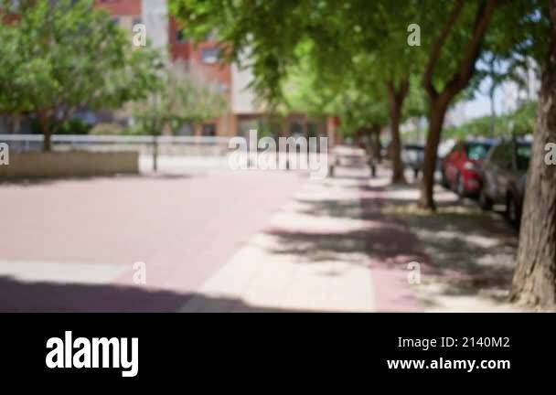 Blurry view of an outdoor urban area with trees, buildings, and parked ...