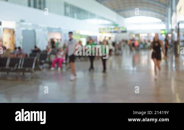 Blurred image of travelers and airport staff walking through a busy ...