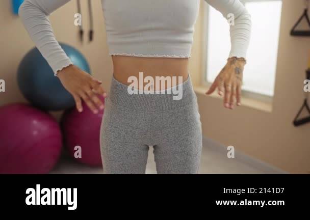Young woman placing hands on waist standing in gym center wearing ...
