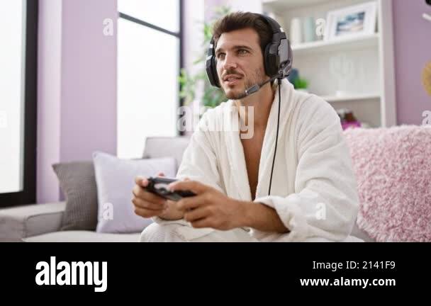 Handsome bearded man in bathrobe playing video games with headset in a ...
