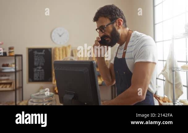 Young man in a bakery shop talking on a smartphone while wearing an ...