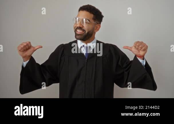 Young hispanic man standing confidently in judge gown pointing proudly ...