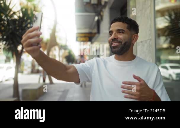 Young man making a video call on mobile phone while standing on an ...