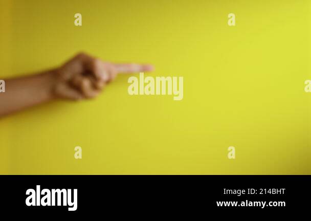 Hand pointing against a vibrant yellow background, capturing the ...
