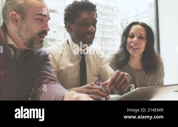 A group of diverse co-workers share a moment of laughter while gathered ...
