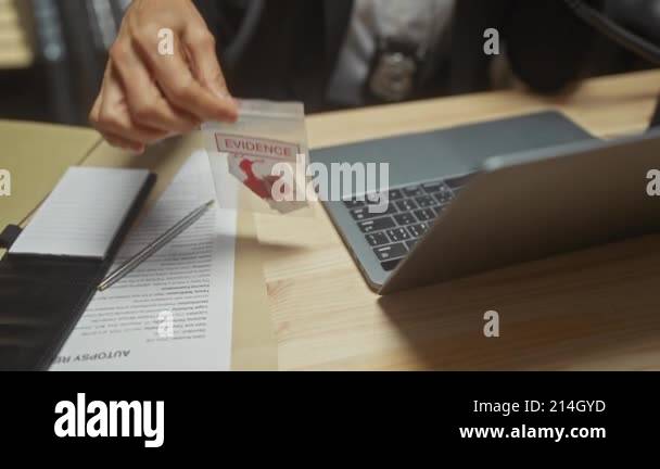 A professional woman examines a bloodstain evidence bag while ...