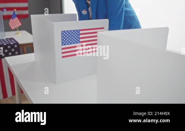 A confident woman voting at an american polling station with booths and ...