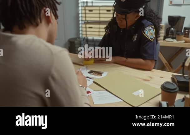 A policewoman investigates fingerprints, interviewing man at police ...
