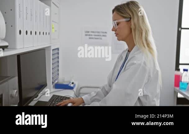 A focused blonde woman scientist examining a specimen in a well ...