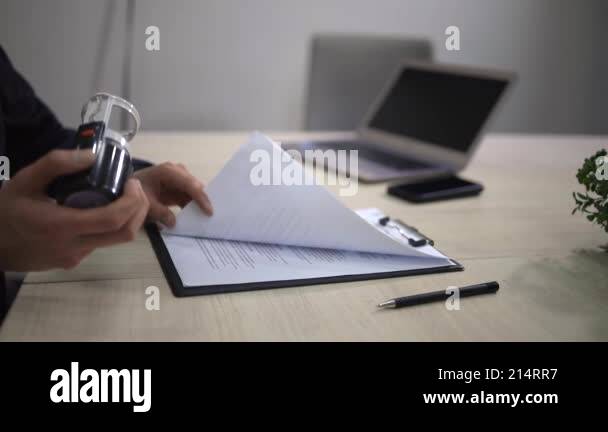 Bank employee puts a seal on financial documents. Person is reviewing important papers in a ...