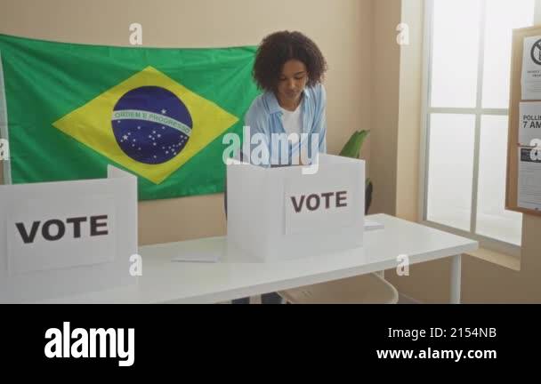 A young black woman with curly hair stands in an indoor electoral room ...