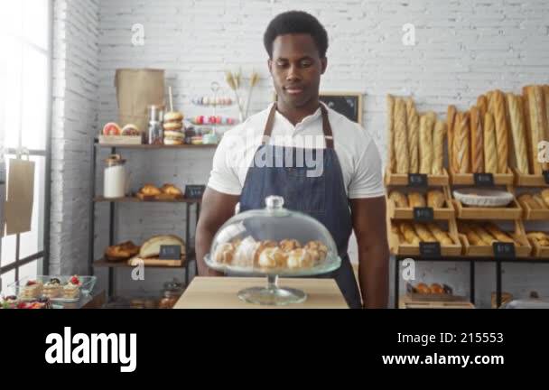 Handsome young man in a bakery shop with fresh pastries and bread ...