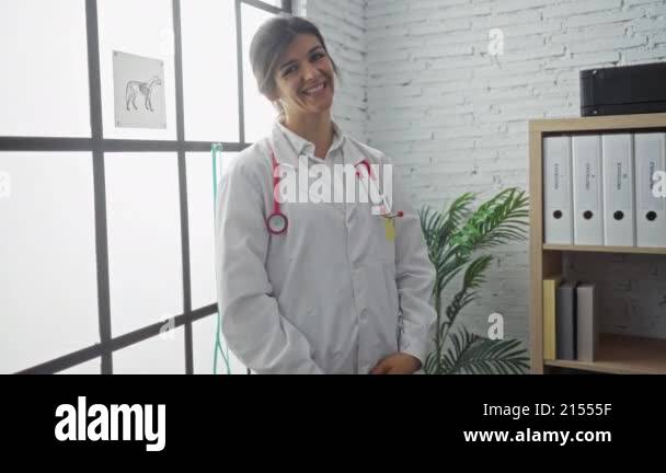 Young female doctor in a clinic room performing an ok gesture, wearing ...