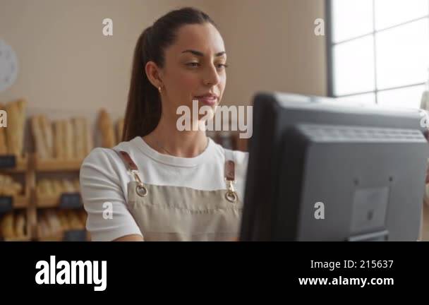 Baker, young hispanic woman in uniform smiling confidently while using ...