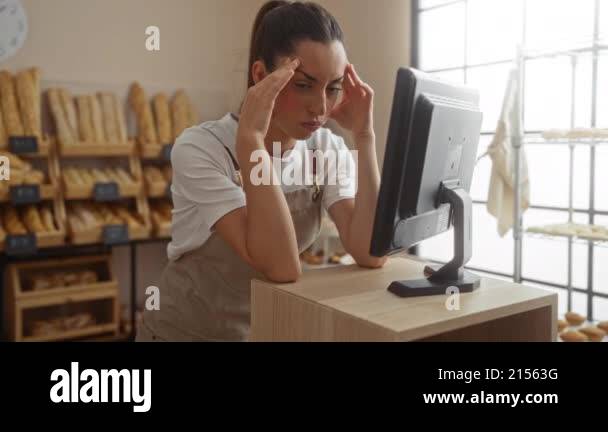 Woman frustrated standing behind counter in bakery shop with shelves of ...