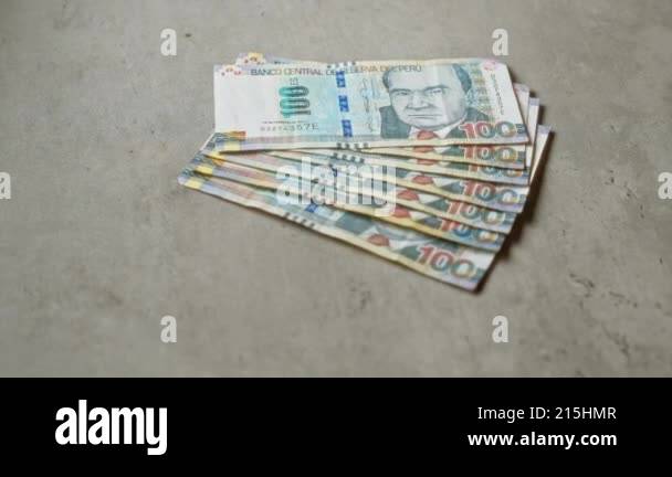 Peruvian banknotes of 100 soles laying on a concrete surface, capturing ...