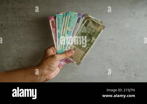 Man's hand holding various denominations of indian rupee notes against ...