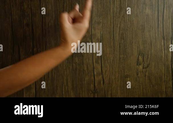 Woman hand making a horn gesture against a textured wood background ...