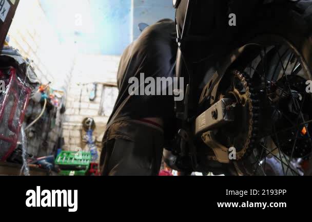 Adult repairman fixing motor of motorbike at workshop. Professional ...