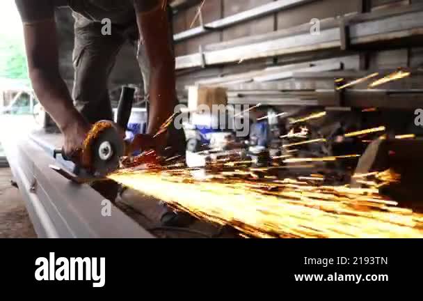 Male hands of young craftsman cuts iron using electric grind wheel at ...