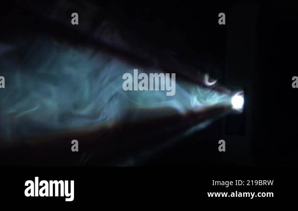 thick smoke glows in the spotlight beams. A home movie projector shines ...