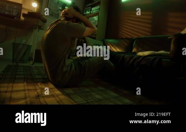 Man doing sit-ups with hands behind his head and knees bent on floor in ...