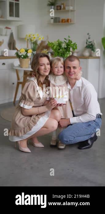 A smiling family with parents and a young child dressed in beige tones ...