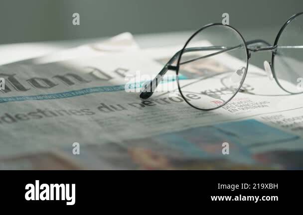 A close up of the glasses on the newspaper. A moving sideways shot ...