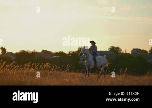 Man in cowboy costume riding horse against sunset. Slow motion footage ...