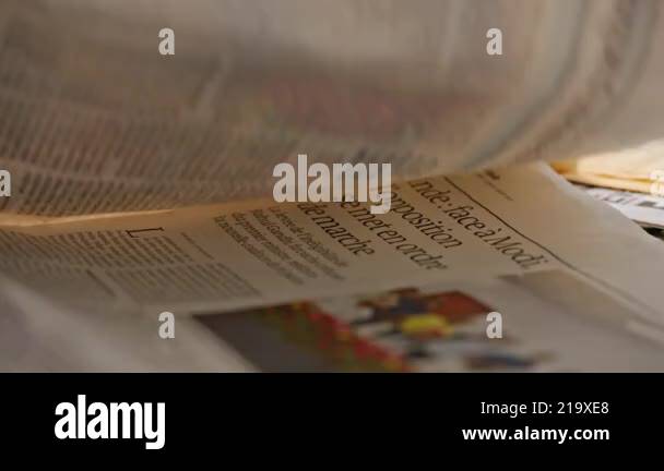 A scattered stack of newspapers on the table. Side view of a mans hand ...