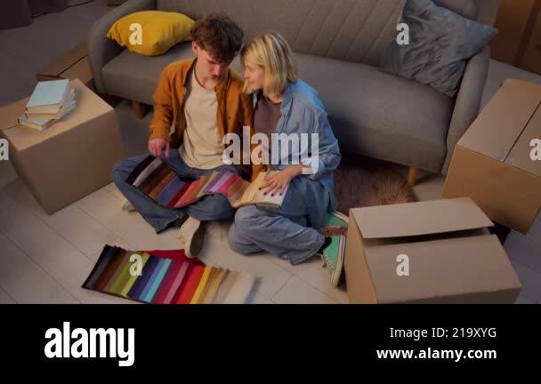 A young man and woman are in the living room discussing a housewarming ...