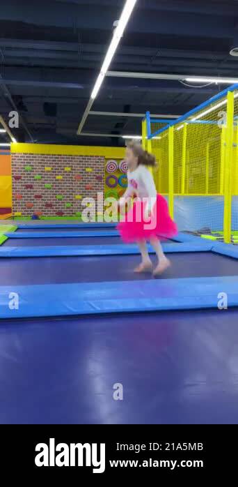 Vertical footage of a cheerful lively girl jumping on a trampoline in a ...