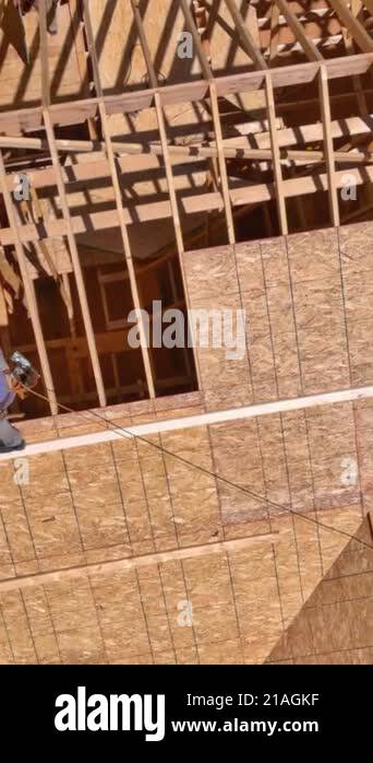 Workers construct wooden framework adding wooden plywood for roofing ...