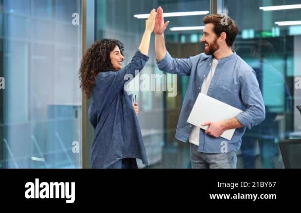 Two happy business professionals high five each other in a modern ...