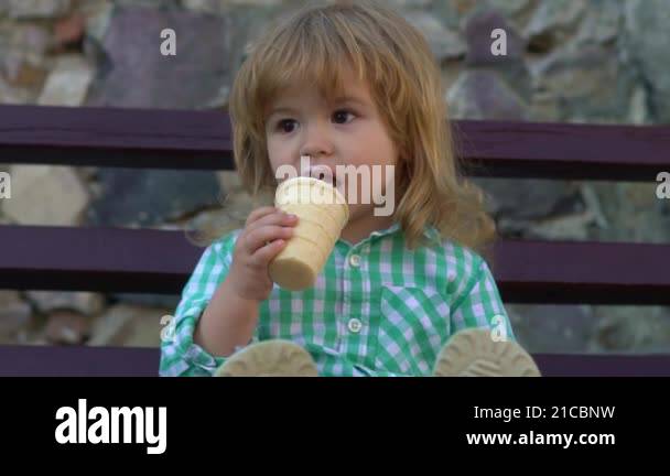 A cute baby eats ice cream. Hungry little kid eating kids ice cream ...