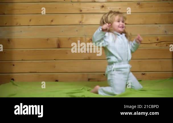Cute little baby child in pajamas laughs and jumps on bed home ...