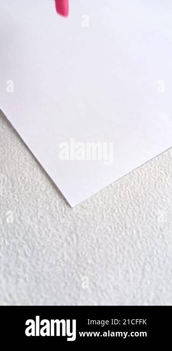 A woman writes with a pink marker pen on a piece of white paper ...