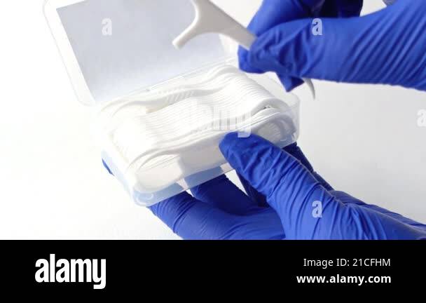 Doctor's hand takes flosser out of plastic container close-up on white ...