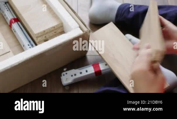 Preschooler pulls out of unpacked box parts assembling furniture. Young ...