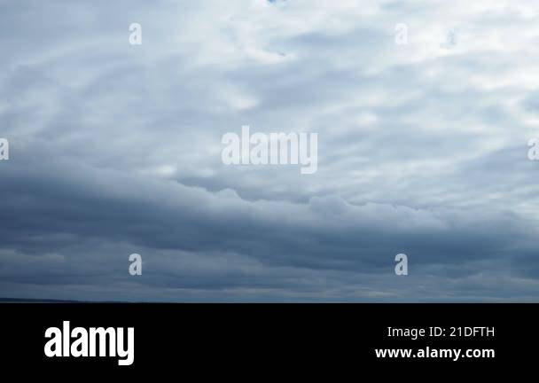 A low, long, heavy, oblong cloud floats across the sky above lake ...