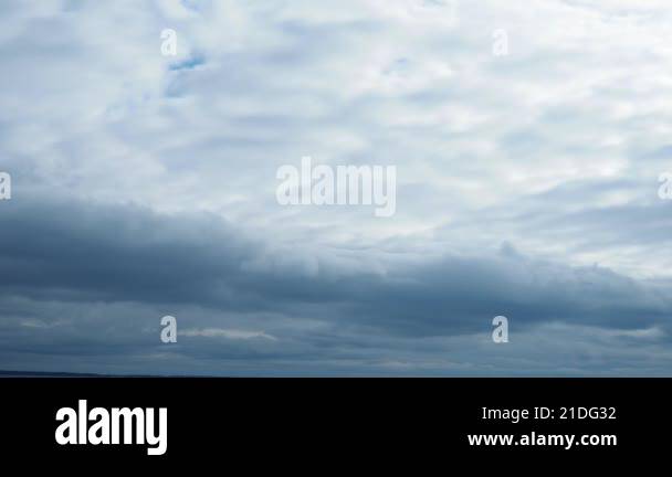 A low, long, heavy, oblong cloud floats across the sky above lake ...
